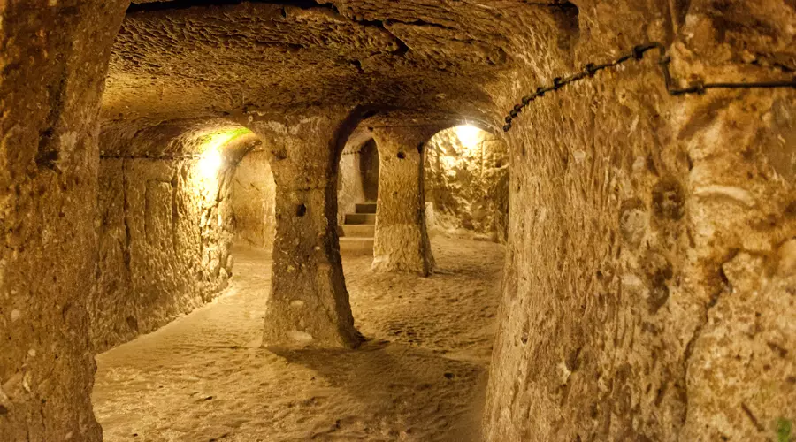 Derinkuyu Existuje několik malých podzemních vesnic roztroušených po celém území Kappadokie, ale Derinkuyu vyčnívá ze všech ostatních. Archeologové datují tento labyrintový komplex do 8. století před naším letopočtem. Derinkuyu klesá až o 18 úrovní pod zemí. V takovém útočišti se uprchlíci neměli čeho bát z dlouhého obléhání - zcela soběstačná metropole by mohla existovat bez zásob z povrchu. Obrovská struktura byla překvapivě nalezena až v roce 1960, a to zcela náhodou.