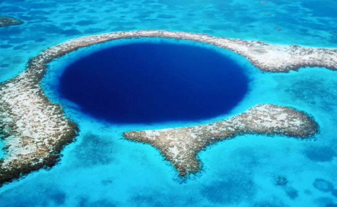 Great Blue Hole Belize Il Great Blue Hole è una gigantesca dolina al largo della costa del Belize. Il buco blu si è formato dalla dissoluzione del calcare, che è stato influenzato dalle correnti marine. Si è formato, a quanto pare, durante diverse ere glaciali. I subacquei di tutto il mondo si riuniscono per rendere omaggio a questa incredibile meraviglia della natura.