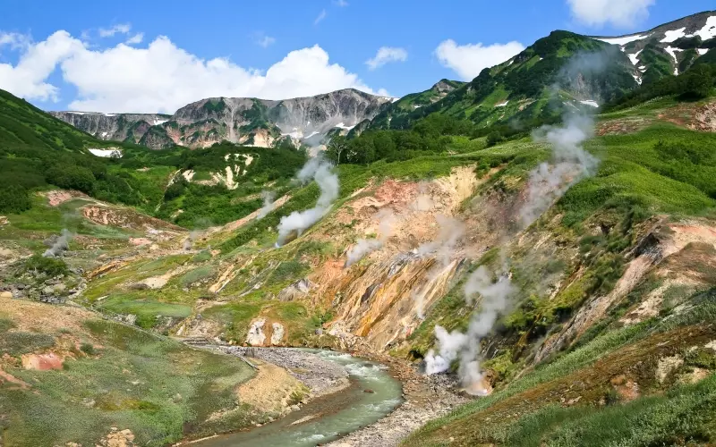 Ikibaya cya Geysers Iki gice gito, cyuzuyemo ibitangaza, cyihishe cyane mumipaka karemano yimisozi ya Kamchatka. Ikibaya cya Geysers cyihishe mu kibaya kitagerwaho ku butaka bwa Kronotsky Biosphere Reserve, kandi ushobora kugera hano ukoresheje kajugujugu gusa. Mu 1934, umukozi w'ikigo gishya cyashinzwe, Tatyana Ustinova, wakoze ubushakashatsi kuri icyo kibaya, yavumbuye geyer nini zirenga 20 hano, atabariyemo amasoko menshi y’amabara y’amashyanyarazi, amasoko abira n’ibiyaga bishyushye. Ahantu heza rwose huzuye huzuzwa icyatsi kibisi-icyatsi kibisi, gishushanya ishusho nziza, nkaho yagaragaye mu nzozi.