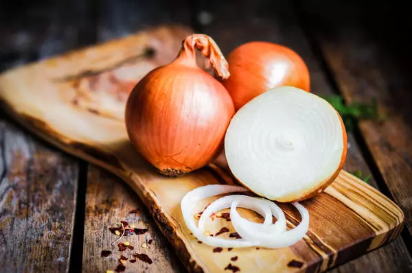 Gëllene Zwiebelen op rustikalem Holzhannergrond