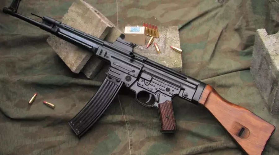 Нямецкі след Прататыпам для канструктара мог паслужыць і нямецкі StG-44. На самай справе, вонкавае падабенства кідаецца ў вочы. А калі яшчэ ўзгадаць, што ў той жа час сам Хуга Шмайссер працаваў на тым жа заводзе, што і Калашнікаў, то выпадкова супадзенне так і зусім выглядае неверагодным. Пераважная большасць заходніх зброевых экспертаў прытрымліваюцца менавіта гэтай версіі. Да прыкладу, шатландскі гісторык Гордан Уільямсан прама піша: «Аднаго погляду на гэта цудоўнае зброю дастаткова, каб зразумець яго ўплыў на ўсё пасляваенны сямейства АК». Прыкладна тыя ж словы паўтарае тэхаскі канструктар Рамсей Теннисон. Ці мог Шмайссер распрацаваць АК-47? Цалкам. Дарэчы, мемуараў аб праведзеным у СССР часу нямецкі канструктар чамусьці не пакінуў.