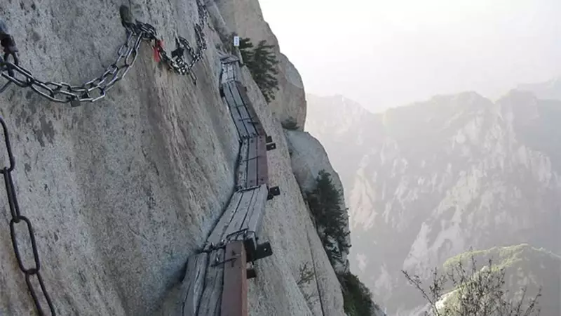 Chine, Huayin, pèlerinage au mont Huashan Il y a un ancien temple au sommet de la montagne à une altitude de 2000 mètres. On peut y accéder en téléphérique ou en escaliers équipés, mais les plus désespérés ne recherchent pas les voies faciles et choisissent un chemin étroit fait de planches d'une cinquantaine de centimètres de large à gravir. Pour l'assurance, les voyageurs sont attachés avec des cordes à des chaînes fixées dans la roche.