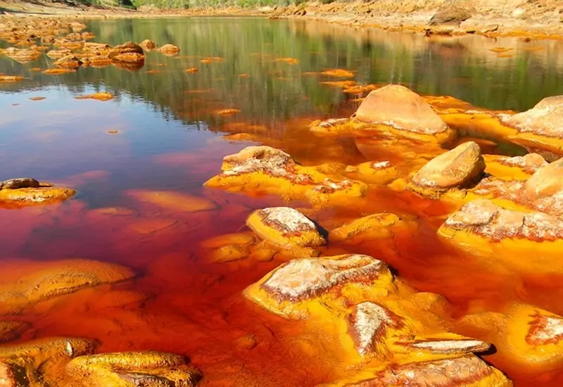 Rio Tinto, Spagna Rio è un fiume, Tinto è rosso. Un tempo il Brasile era così chiamato dai colonialisti portoghesi con il nome locale di mogano. La provincia spagnola dell'Andalusia è ancora in Europa. Il guaio è che da più di tremila anni lì si estrae oro, argento, rame, nichel, molibdeno... Nel Medioevo veniva estratto anche il mercurio. Il risultato dell'inquinamento del lago, in cui confluiscono numerosi canali di scolo, è prevedibile e può essere visto nell'illustrazione. Stranamente, lì vivono batteri estremi, che non hanno bisogno di aria (sono anaerobici), ma hanno davvero bisogno di azoto. Gli astrobiologi ritengono che questo tipo di batteri attecchirà bene su Marte.