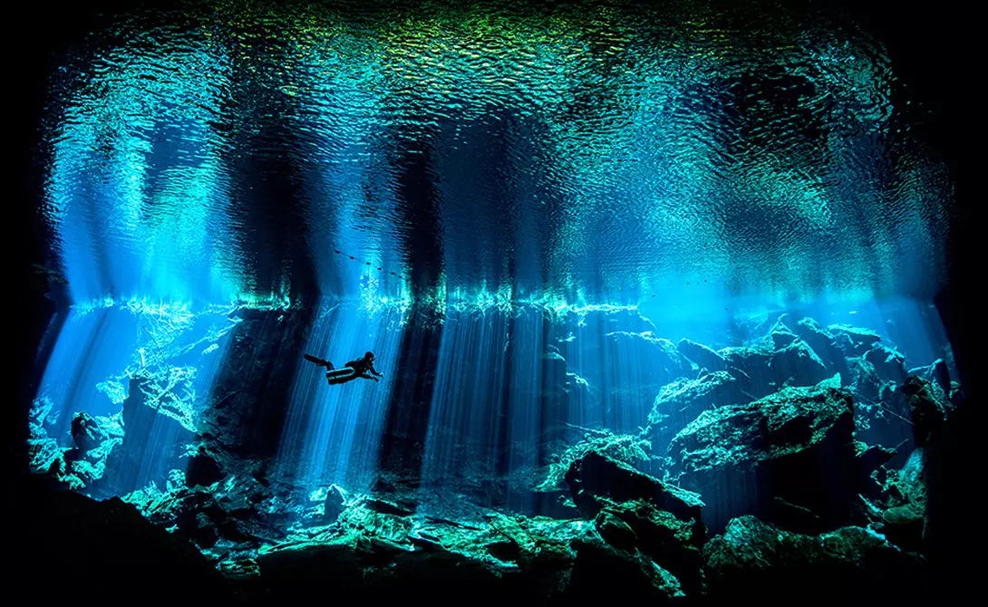 Getting Out of the Blue Nominatie: Cave Diving Door Nick Blake Blake's foto ziet eruit als een echt kunstwerk. Deze foto is genomen in een van de cenotes van het schiereiland Yucatan: de zon drong door de waterkolom de grot binnen en veranderde de wereld om ons heen in een theatraal decor.