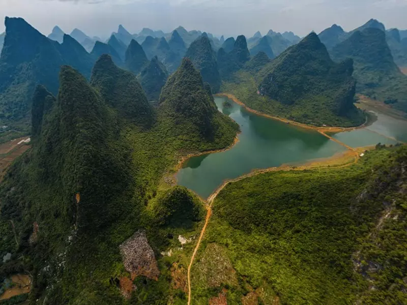 Guilin, China O duro si ibikan wa ni guusu ti China, ni bèbe Odò Lijiang. Itumọ lati Ilu Kannada “Guilin” tumọ si “igbo ti awọn igi kasia.” A ko yan orukọ naa lairotẹlẹ, nitori awọn ọwọn ti ile simenti ti agbegbe ni irisi jọ igbo igbo. Awọn oke -nla ti bo pẹlu awọn ohun ọgbin ti o nipọn, ti o ni awọn ajara, awọn igi ati awọn ododo. Ọna ti o dara julọ lati rii gbogbo ẹwa ti iseda ni lati rin irin -ajo ọkọ oju omi lori Odò Lijiang lati Guilin si Yangshuo.