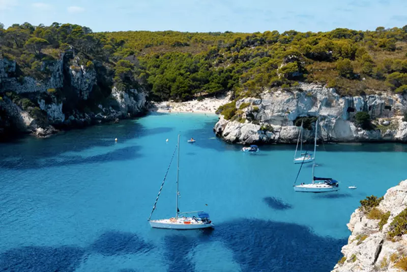 Cala Macareleta, Menorca, Spain Ang buong baybayin ng Menorca ay binubuo ng mga beach at coves, habang ang tubig ay malinaw sa kristal saanman. Ang pinagkaiba ng Cala Macareleta mula sa iba pang mga lugar ay protektado ito mula sa hangin ng mga nangungulag na kagubatan.