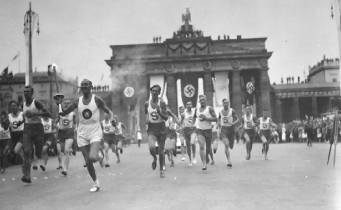 Den olympiska facklan Liksom alla teatraliska monologer behövde Hitlers tal ett anständigt set - annars skulle magi inte fungera. Självklart var allt klart långt innan spelen började. Den första (och mycket slående) symbolen för tysk uppriktighet var den återupplivade ritualen att föra facklan från Olympia till Tyskland. Dess eviga låga symboliserade den inre enheten hos alla världens folk. Den historiska bakgrunden var uppenbar: för århundraden sedan invigde en ensam löpare med en fackla de allra första spelen i Grekland. Tyska idrottare bar facklan tänd i grekiska Olympia till Berlin med stafett - så här är den tradition som fortfarande finns idag.