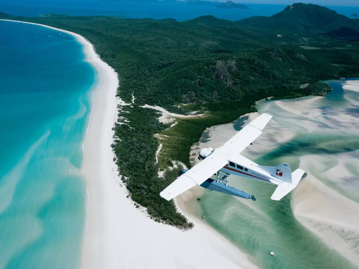 Whitehaven Trinity Island, Australien Paradise Beach halbiert fast eine weite Bucht. Weißer Sand und türkisfarbene Wellen verwandeln sich bei Sonnenuntergang in ein wahres Kunstwerk. Entspannen sollte man sich hier jedoch nicht: Haie sind häufige Gäste dieser Gewässer.