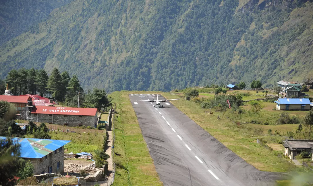 Lukla, Nepal Tenzing e o aeroporto de Hillary Moitos escaladores que decidiron conquistar o monte Everest comezan a súa viaxe ao cumio do mundo dende a cidade de Lukla. O aeroporto local que leva o nome de Tanzing e Hillary foi creado para tales aventureiros, para probar a súa seriedade e resistencia. O porto aéreo está situado a 2900 metros de altitude sobre o nivel do mar. A pista está rodeada de picos e remata nun penedo. O xa difícil ambiente de despegue e aterraxe vese dificultado polas nubes que se acumulan arredor.