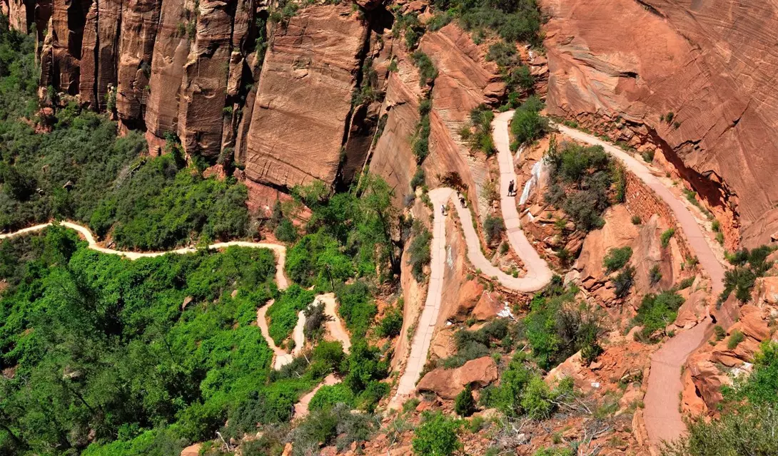 Zion Angel Trail, USA Ferðamenn ganga um tignarlegt landslag Zion National Park, Utah. Slóðin felur í sér þrönga fjallgarða með djúpum hólfum, þar sem flestir göngufólk notar keðjur til að ljúka slóðinni þegar hápunktur slóðarinnar er, sem býður upp á töfrandi 360 gráðu útsýni sem verðlaun.