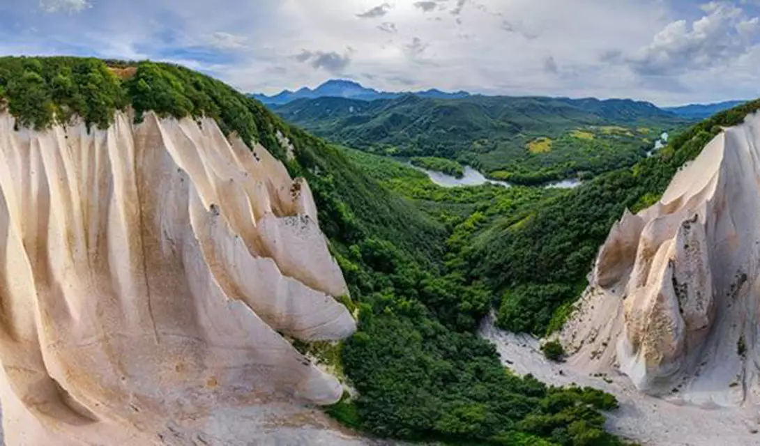 Abunda verda vegetaĵaro nur akcentas la severan belecon de la elmontritaj klifoj.