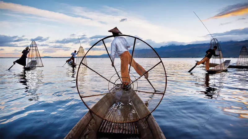 Pescatori all'alba. La tecnica di pesca del popolo Inta, che vive vicino al lago Inle, dal lato ricorda un'insolita coreografia calligrafica: in una mano i pescatori tengono una rete e nell'altra un remo, che controllano con il piede.