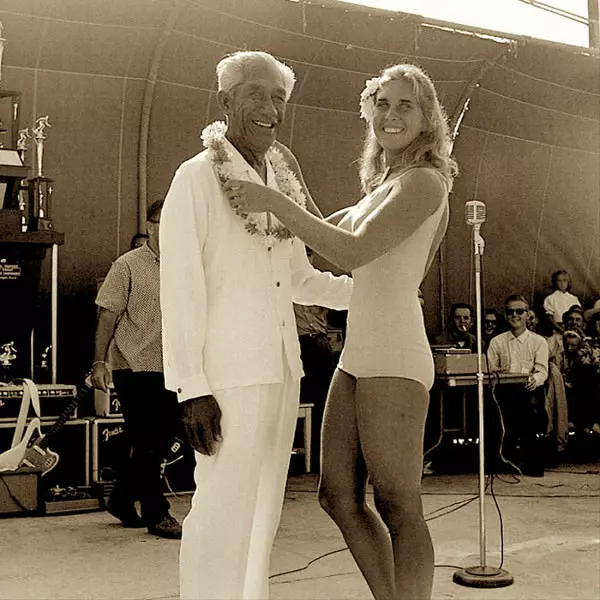 Candy Calhoun entuk semangat surfing saka ibune, Marge. Gambar karo dheweke karo bapak surfing modern lan juara renang Olimpiade Duke Kahanamoku ing Kejuaraan Surf AS ing Pantai Huntington ing California kidul. 1964 taun.